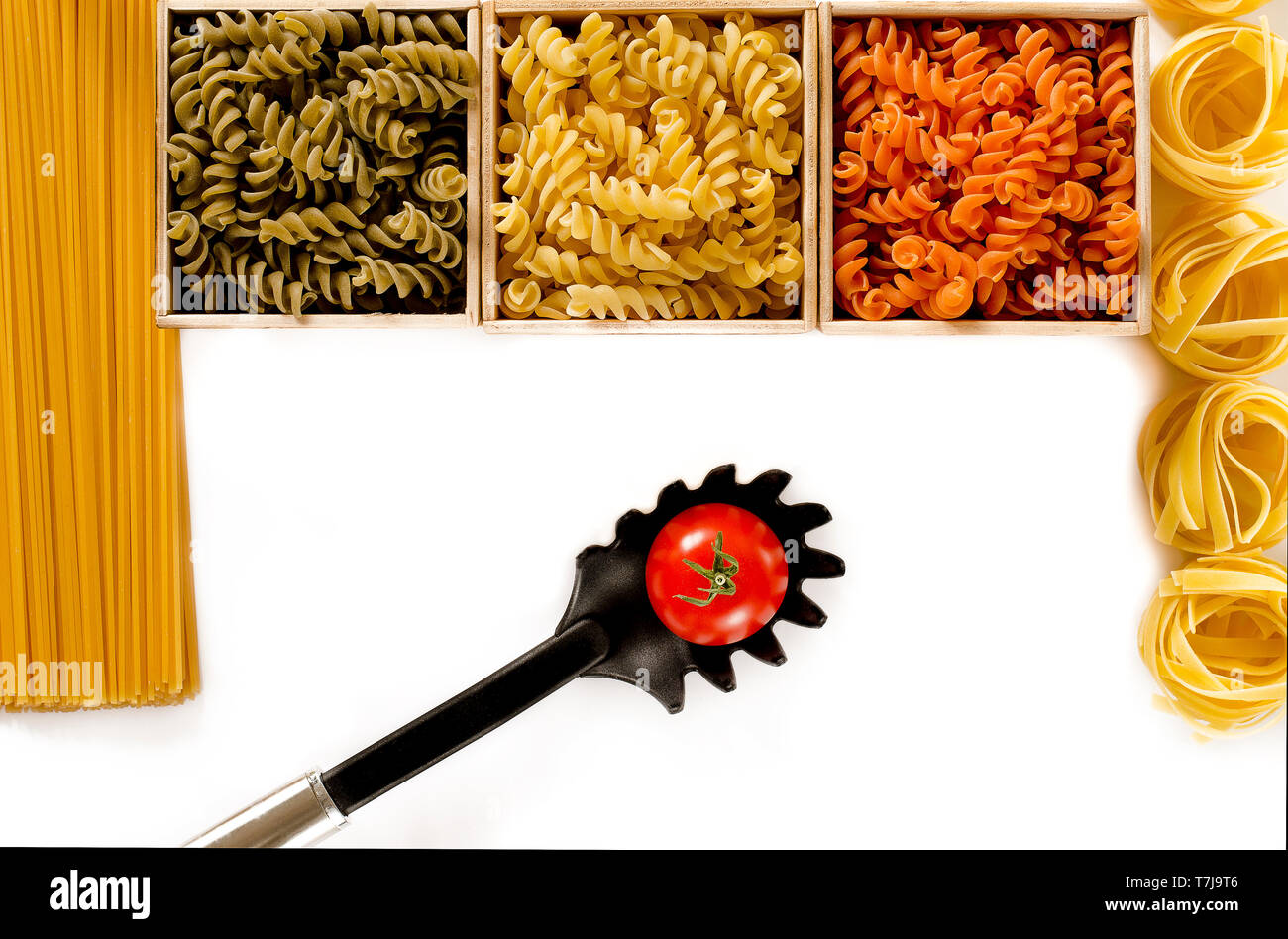 Multi-colored pasta in the form of spirals lie in wooden boxes that ...