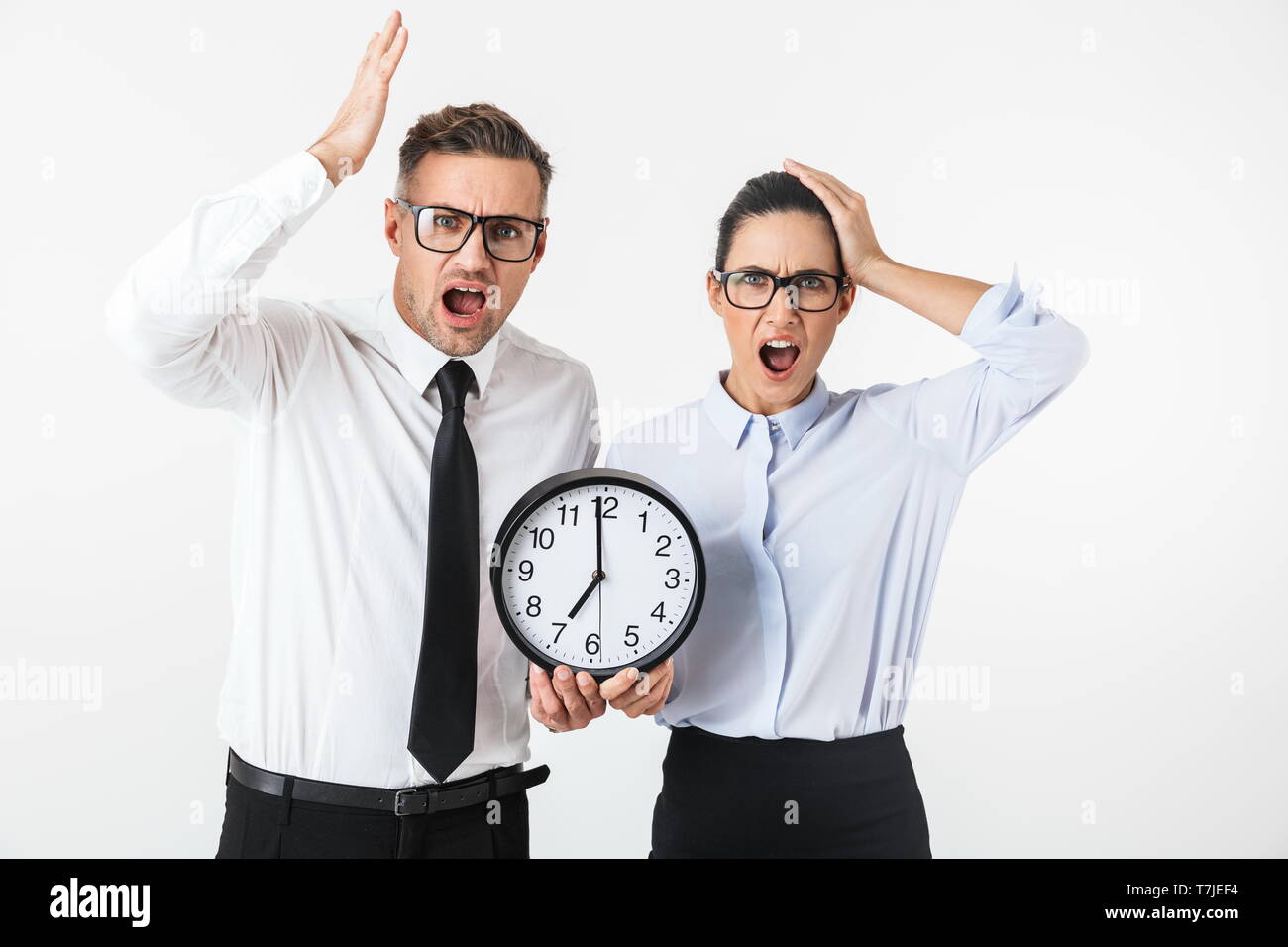 Couple of shocked colleagues wearing formal clothing standing isolated ...