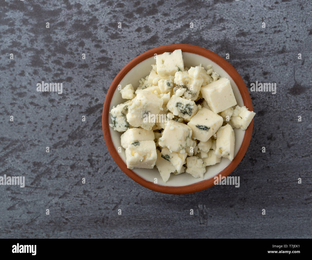 Overhead view of a portion of crumbled blue cheese in a small bowl atop ...