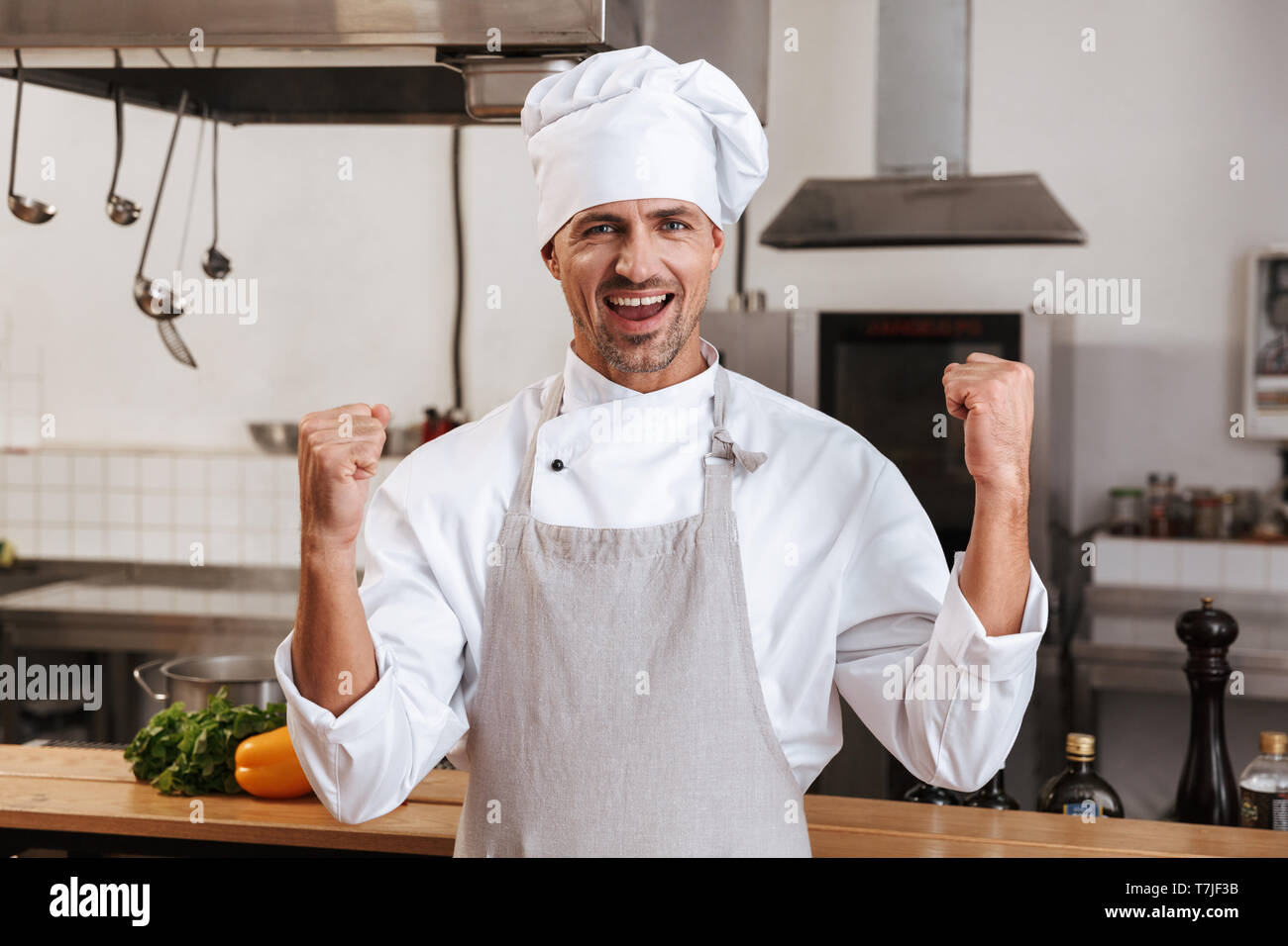 Image of happy male chief in white uniform smiling while standing at ...