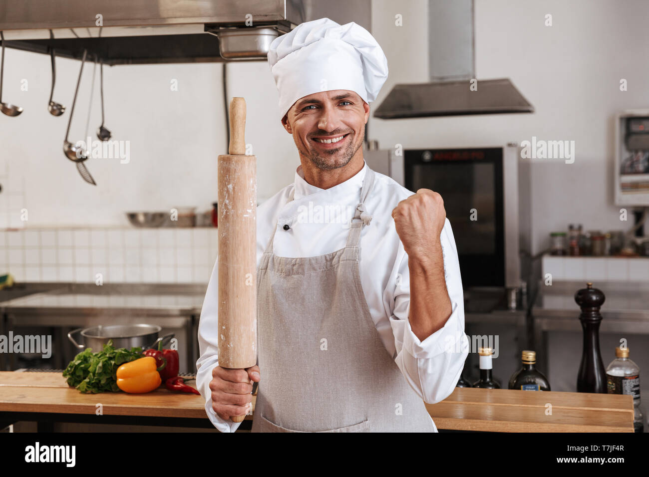 Photo of caucasian male chief in white uniform holding rolling pin ...