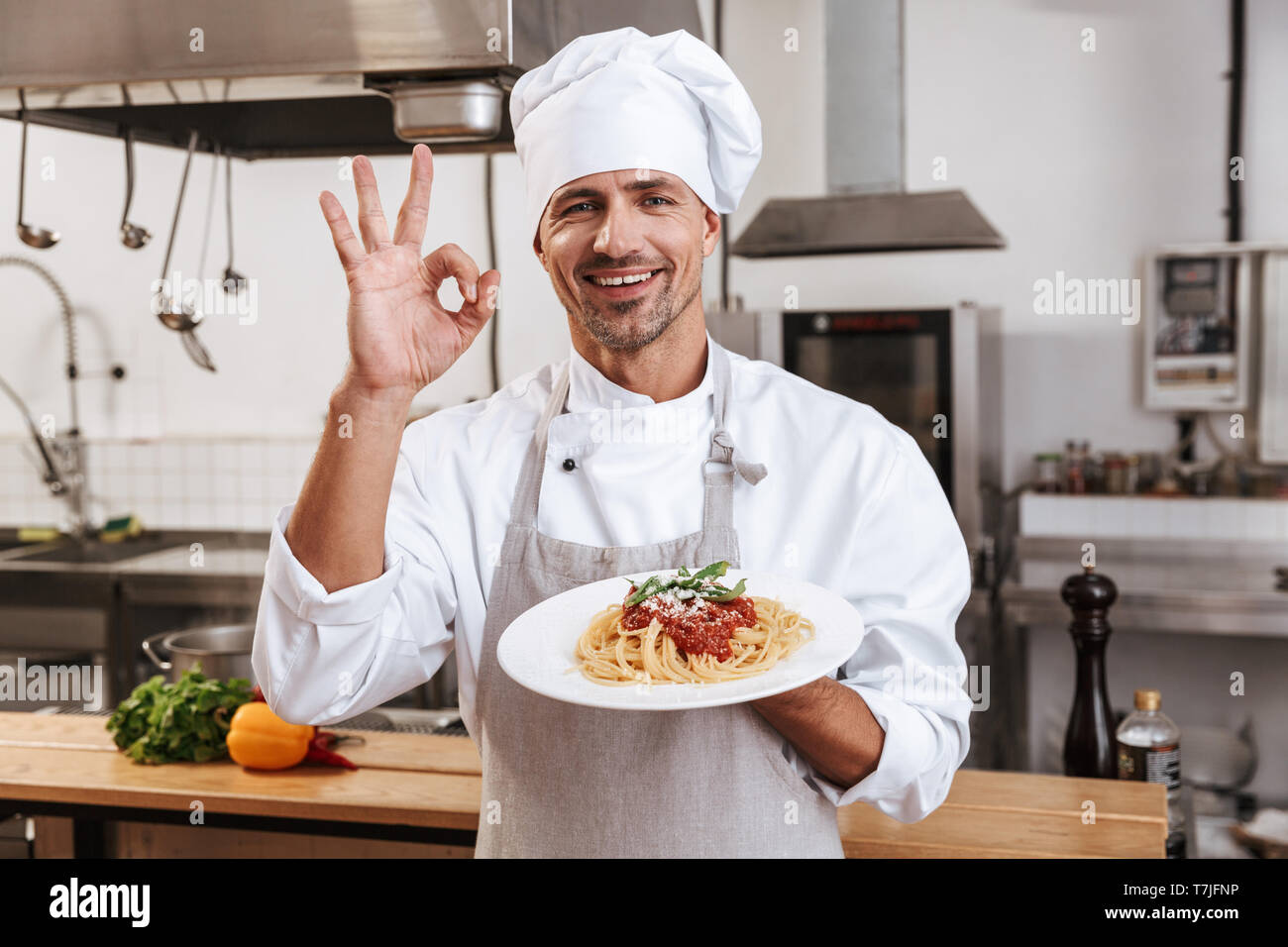 Photo of european male chief in white uniform holding plate with meal ...