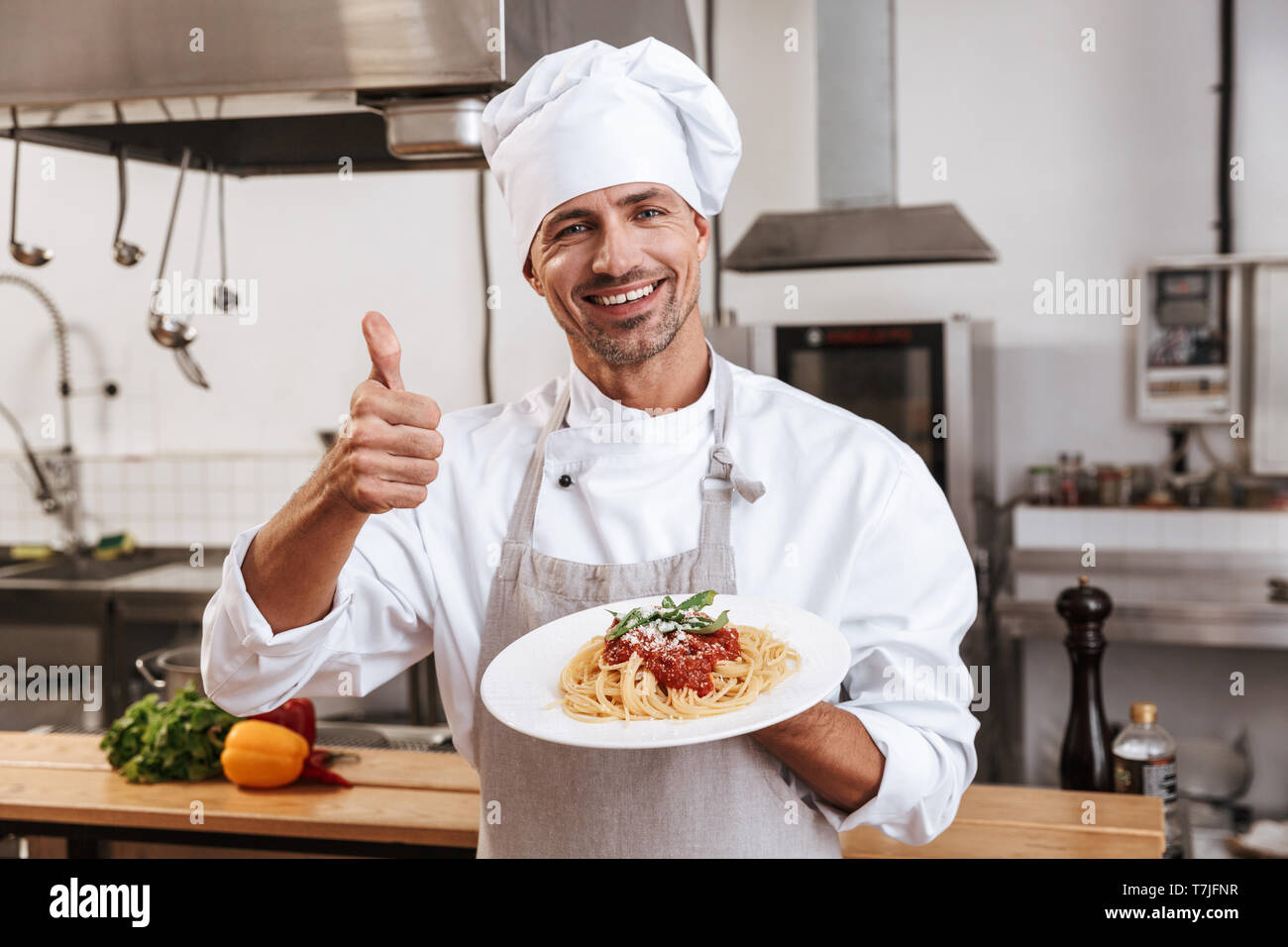 Photo of adult male chief in white uniform holding plate with meal ...