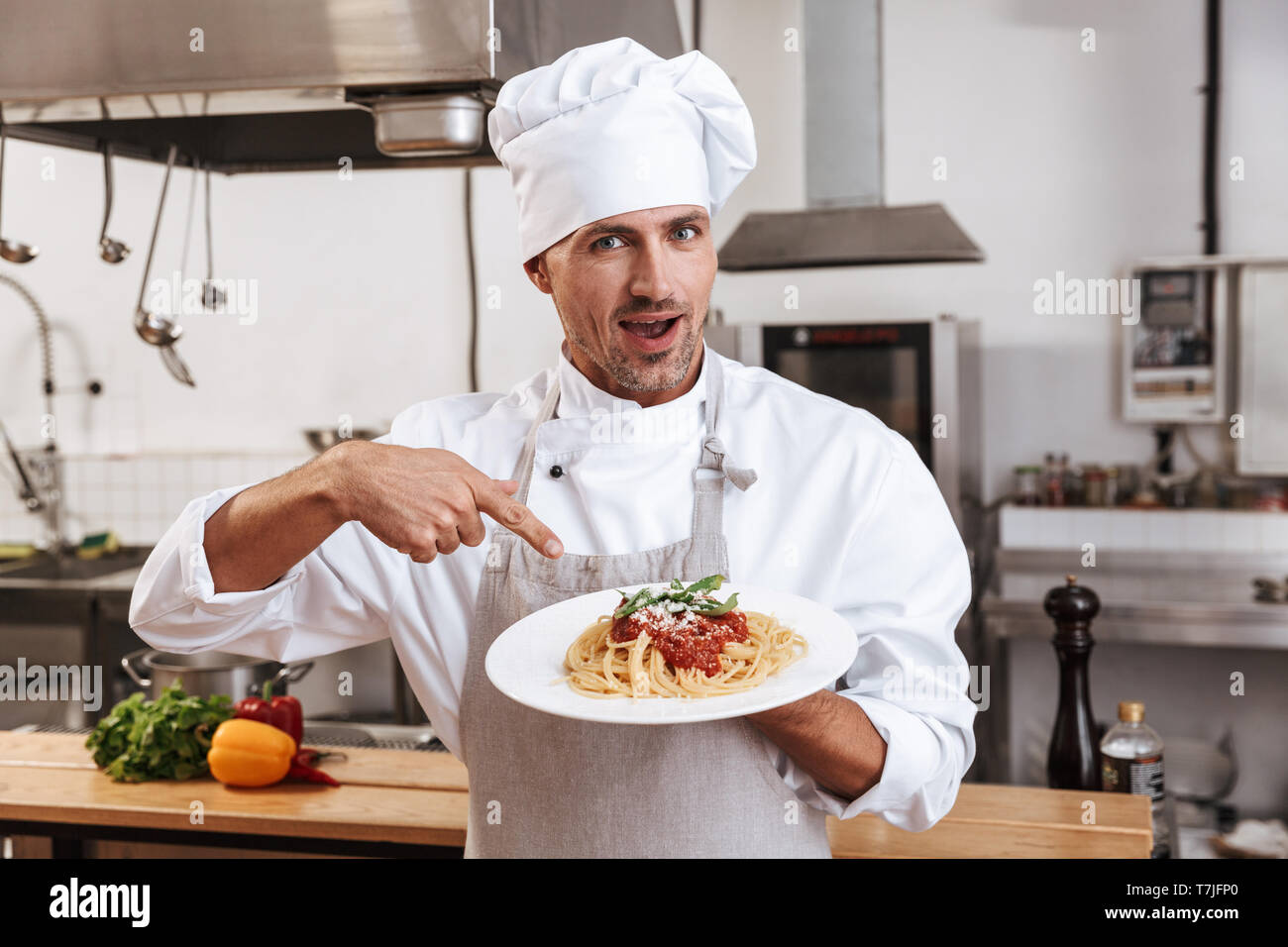 Photo of professional male chief in white uniform holding plate with ...