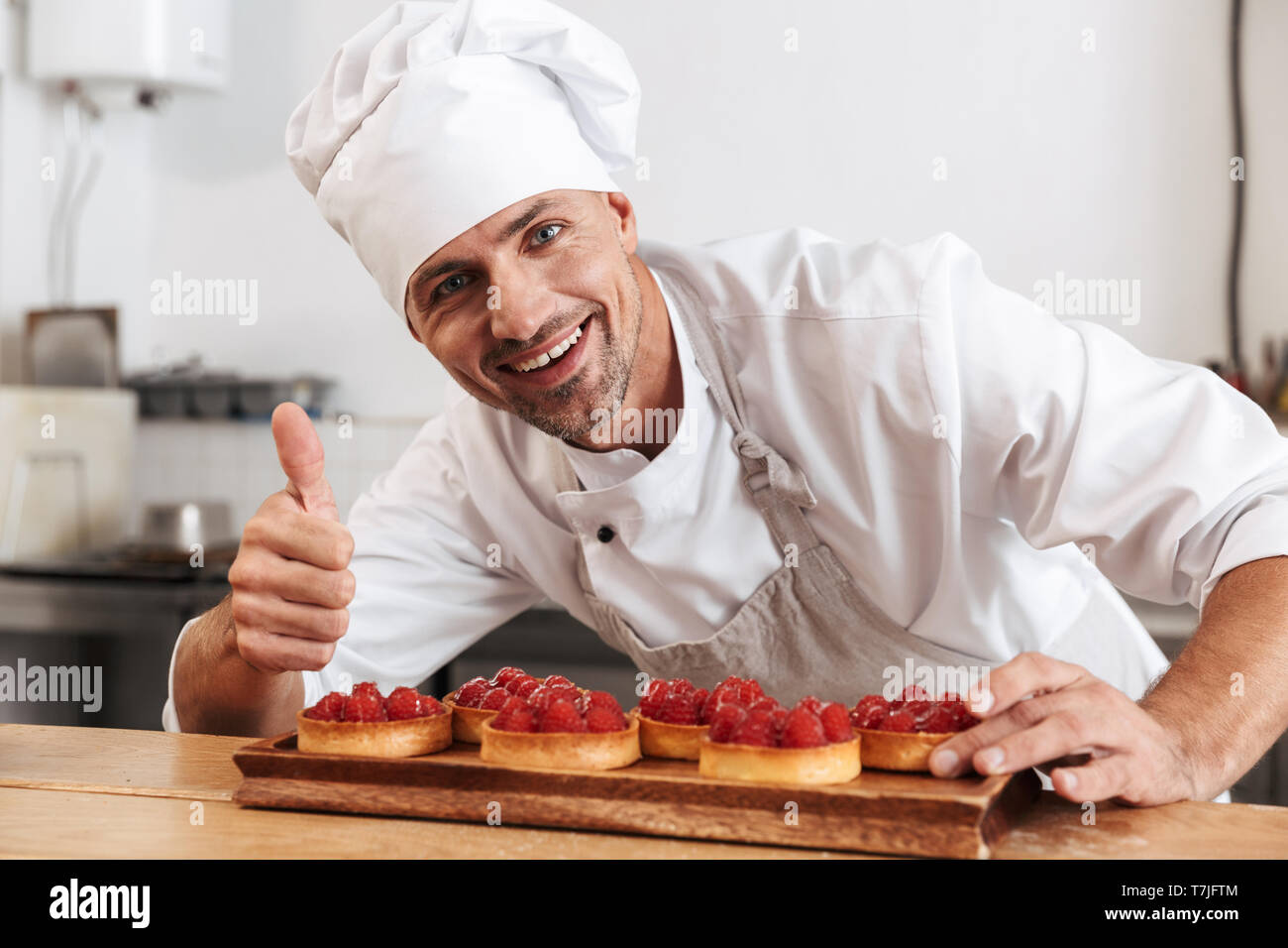 Photo of professional male chief in white uniform holding plate with ...