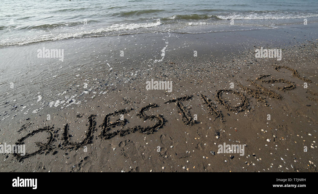 Questions with question mark written in large letters on the beach ...