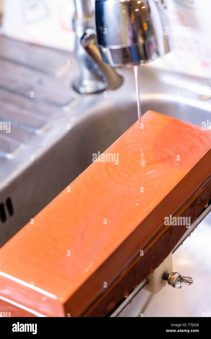 woman professional chef hands hold knife for whetting on whetstone ...
