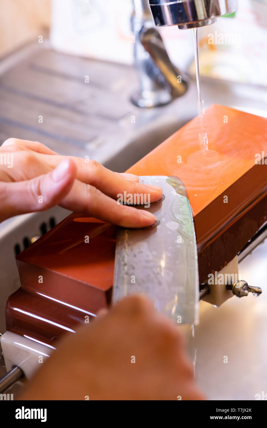 woman professional chef hands hold knife for whetting on whetstone ...