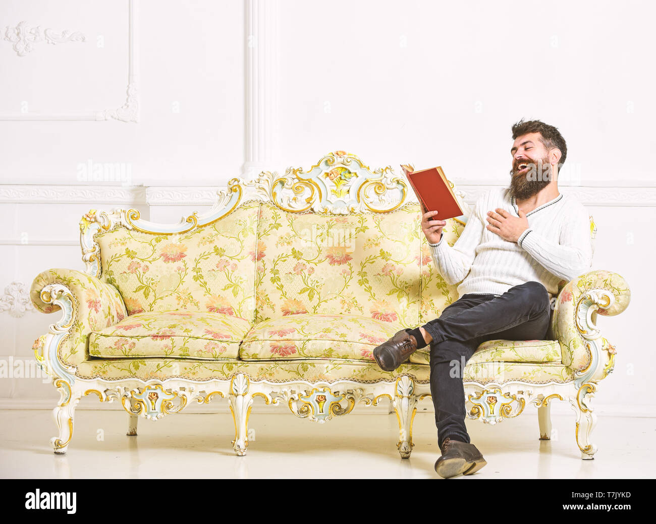 Guy reading old book with enjoyment. Man with beard and mustache sits ...