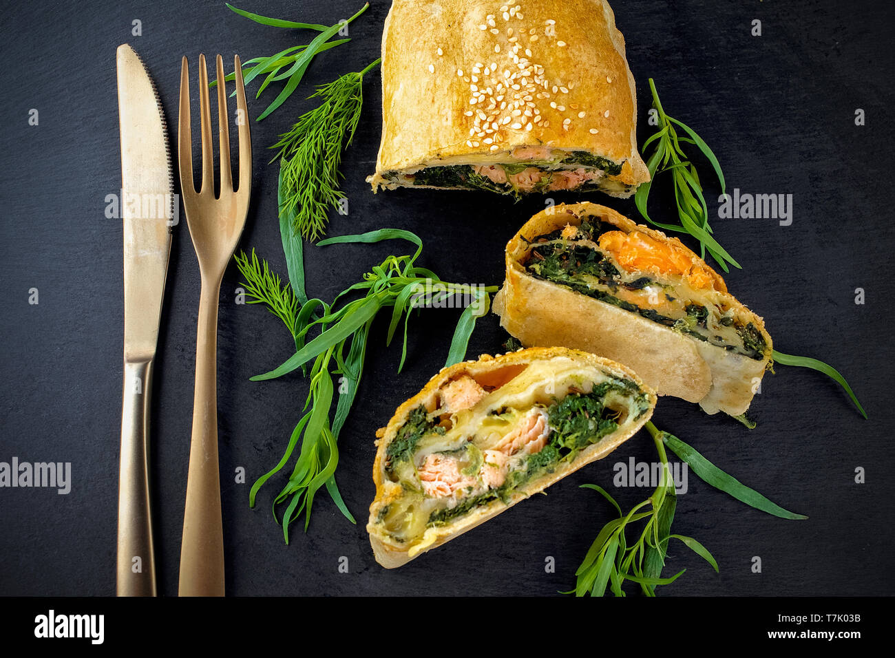 strudel with fish and spinach on a black background Stock Photo - Alamy
