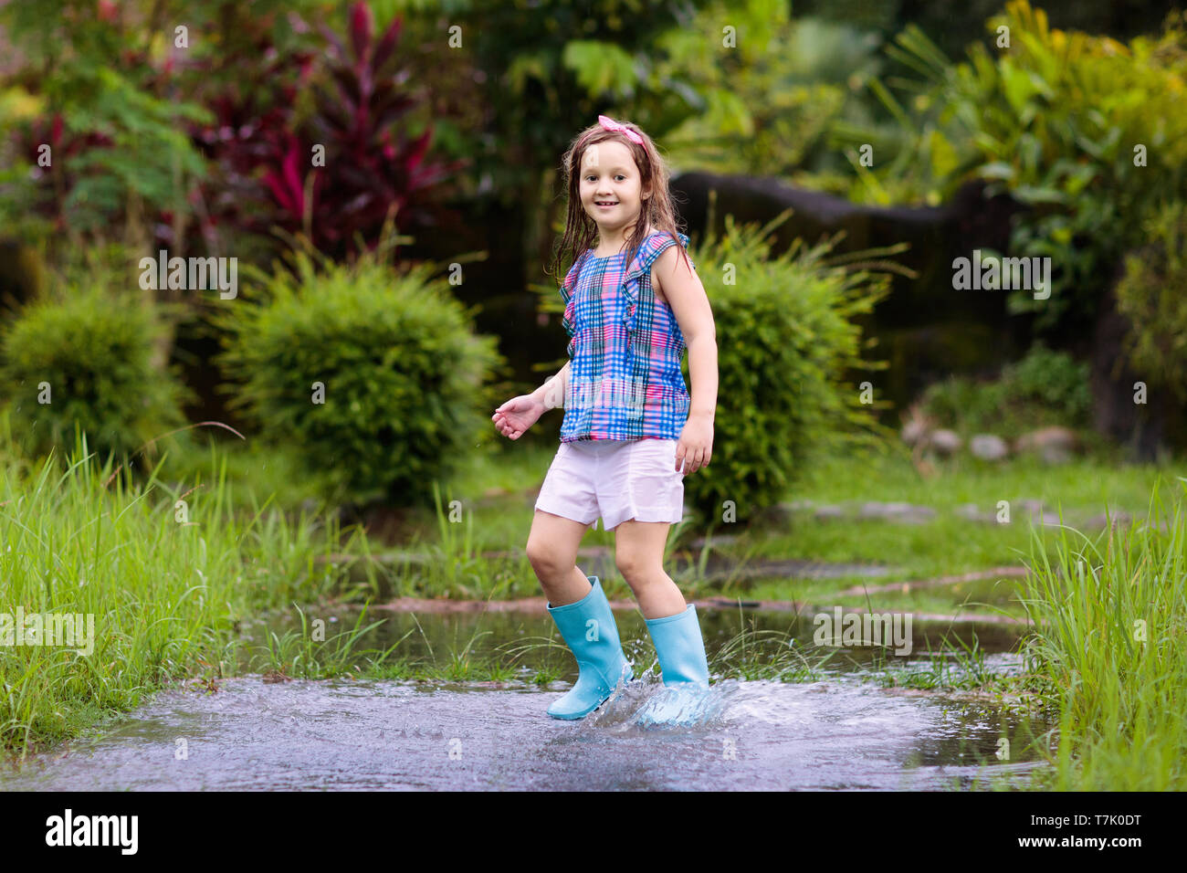 Kid playing out in the rain. Children with umbrella and rain boots play ...