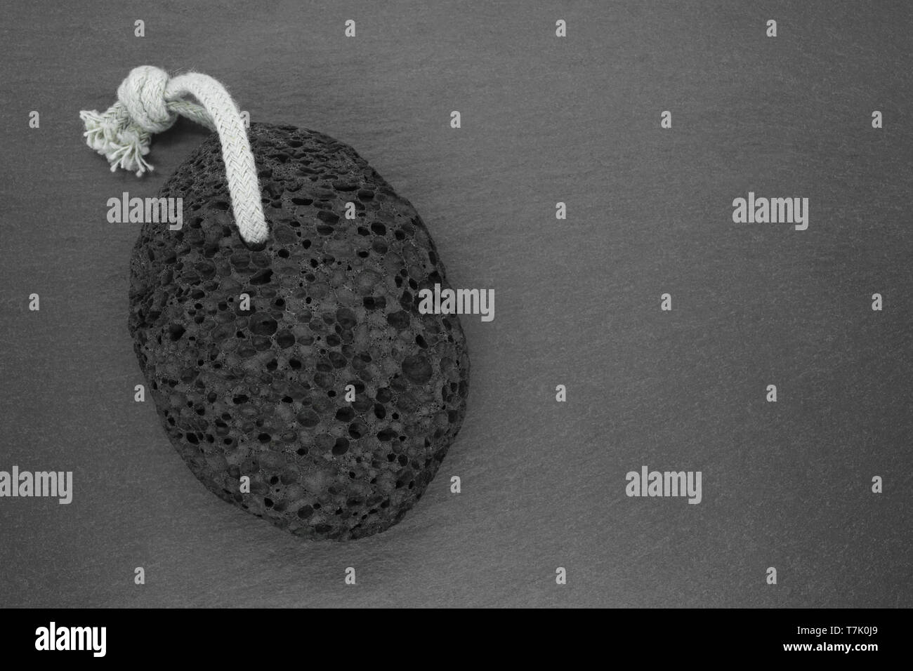 Black pumice stone with white rope for spa on grey stone background ...
