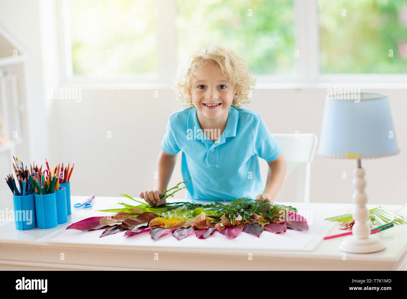 Child creating picture with colorful leaves. Art and crafts for kids ...