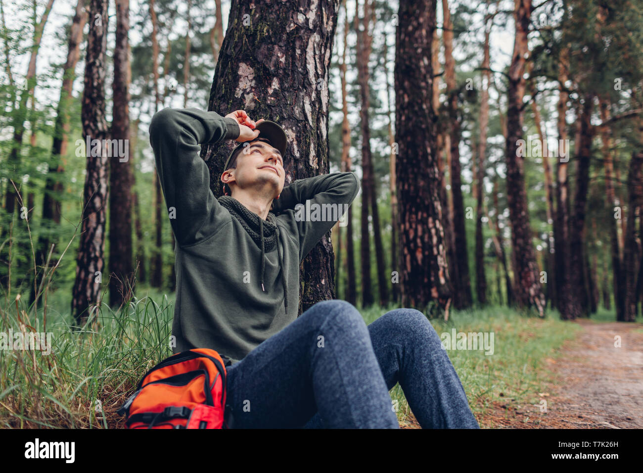 Tired man tourist sleeping in spring forest by tree. Traveler stopped ...