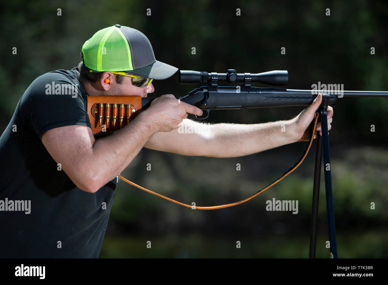 A man aiming a rifle that is resting on shooting sticks Stock Photo - Alamy