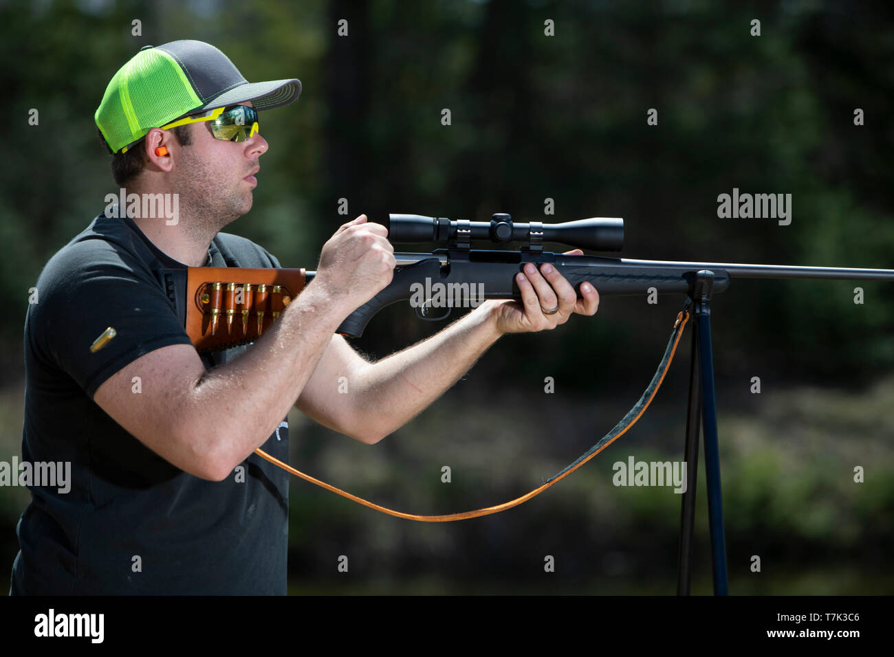 A man cocking a bolt-action rifle with the ejected shell in the air ...