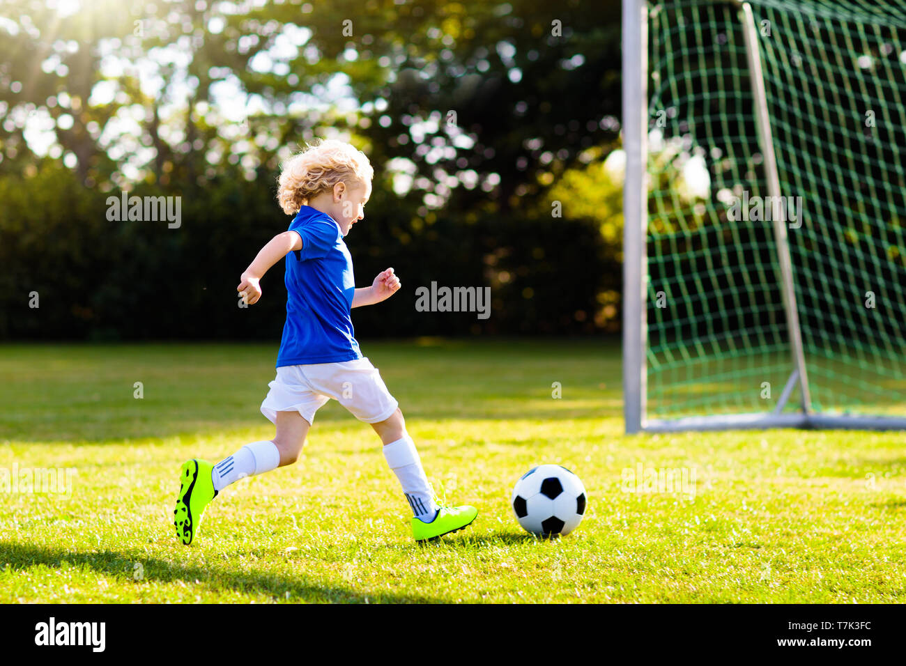 Kids play football on outdoor field. Children score a goal during ...