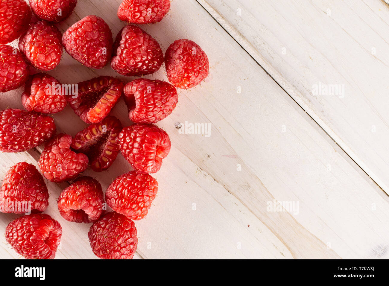 Lot of whole fresh red raspberry with copyspace flatlay on white wood ...