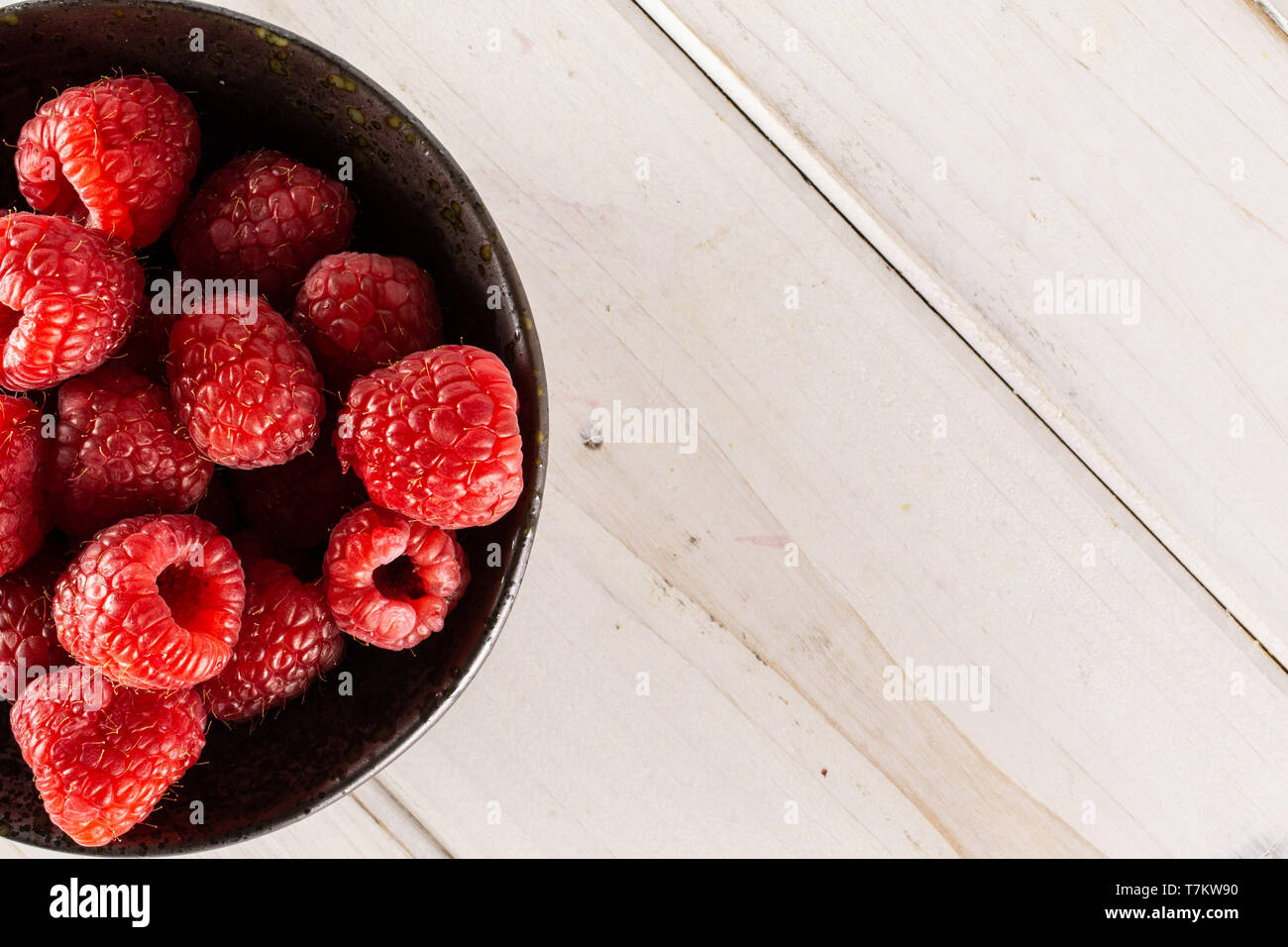 Lot of whole fresh red raspberry on grey ceramic plate flatlay on white ...
