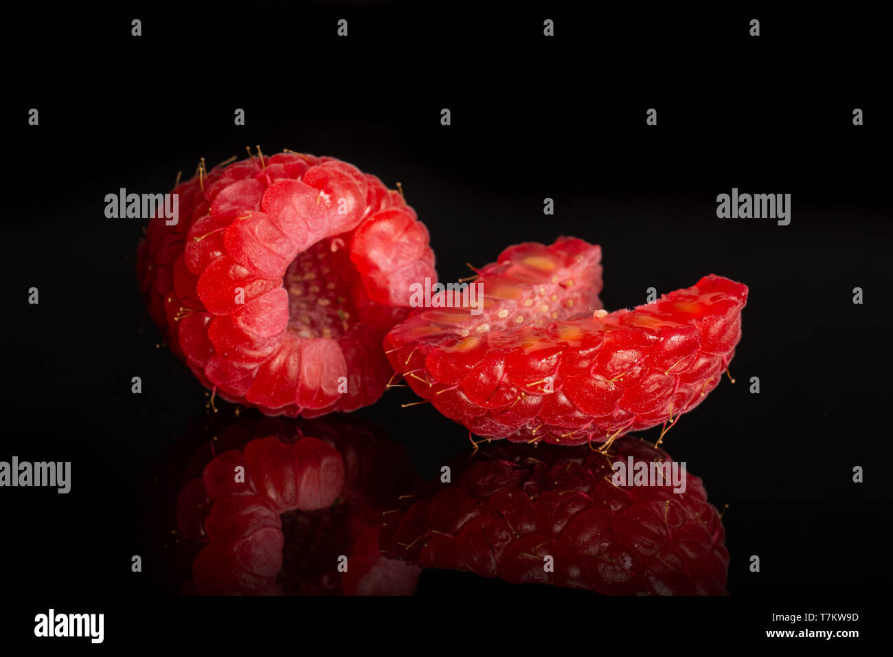 Group of one whole one half of fresh red raspberry isolated on black ...