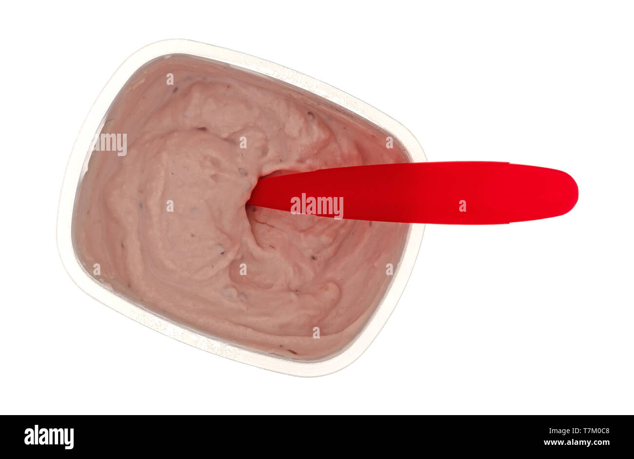 Overhead view of a small container of red raspberry yogurt with a spoon ...