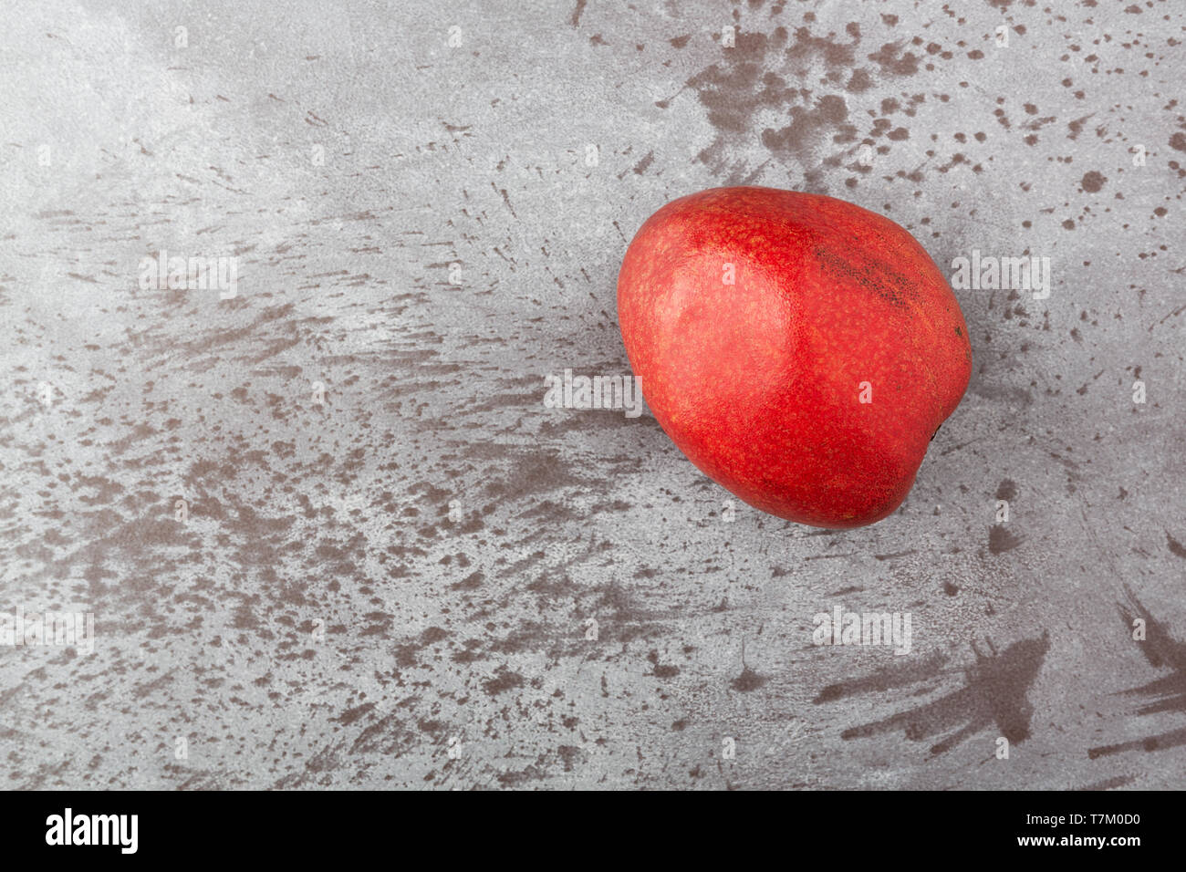 Top view of a single ripe red anjou pear offset on a gray mottled ...