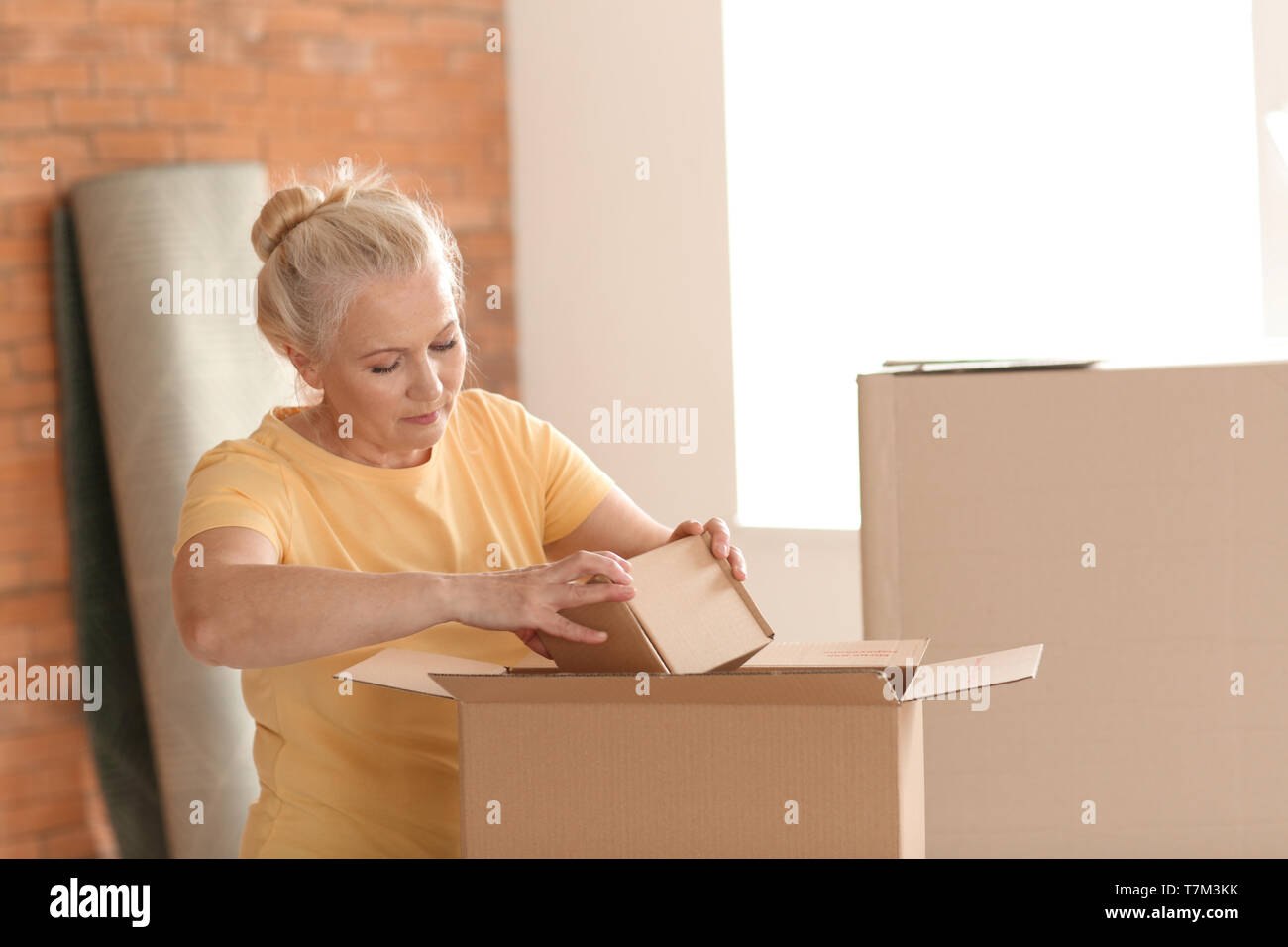 Mature woman with moving boxes at new home Stock Photo - Alamy