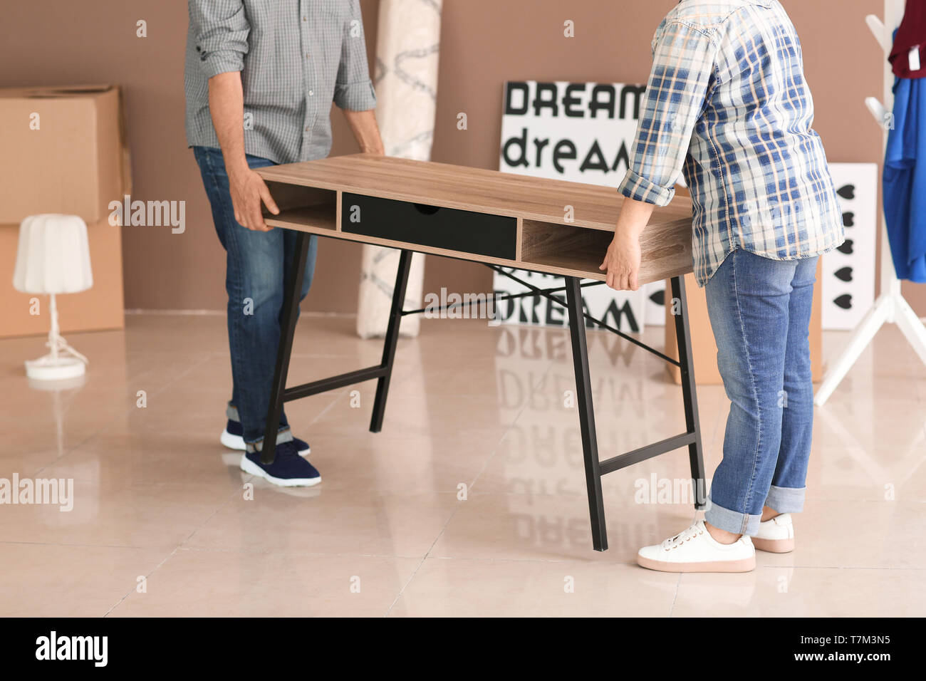 Mature couple carrying table in room after moving to new home Stock ...