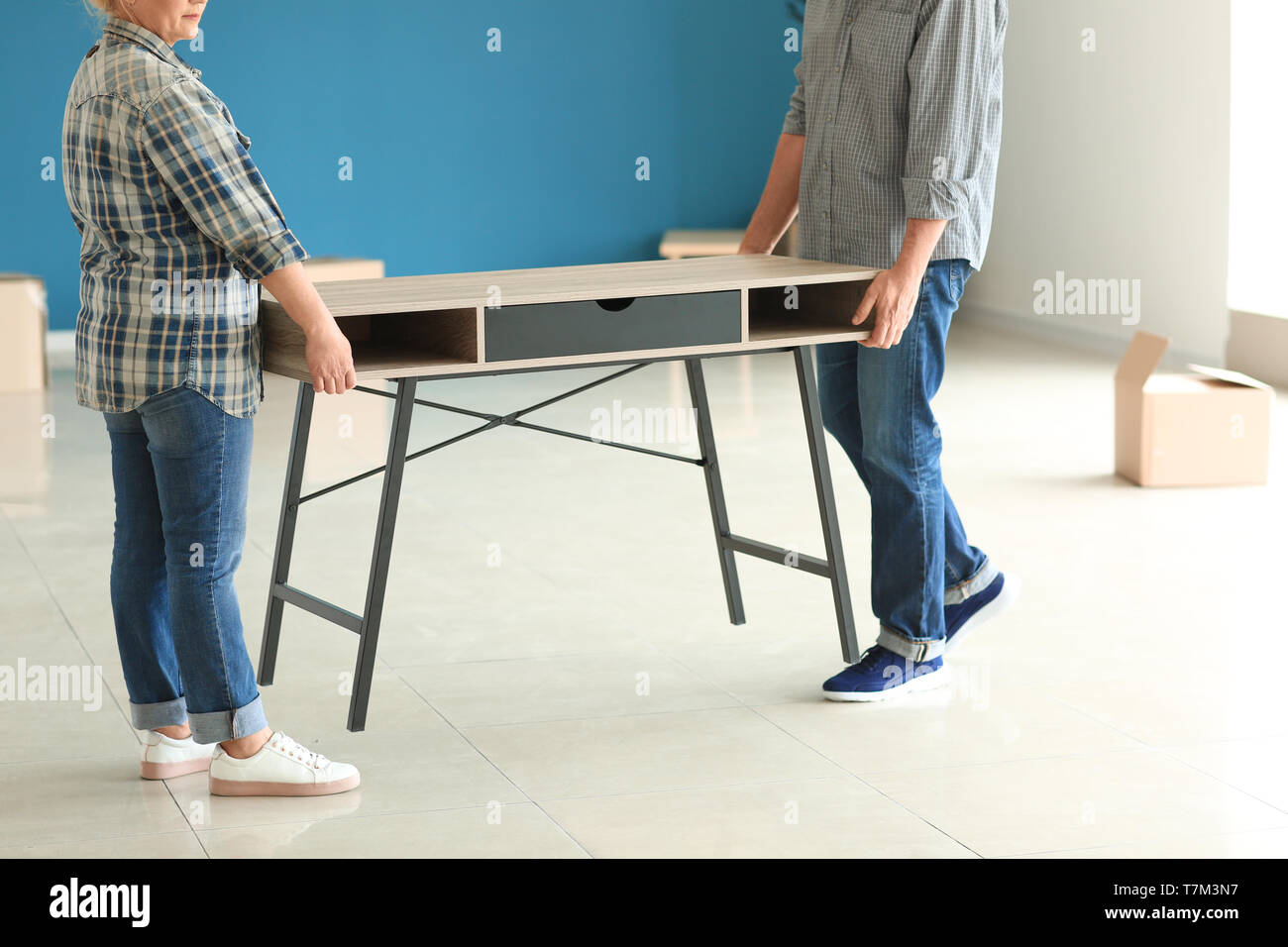 Mature couple carrying table in room after moving to new home Stock ...