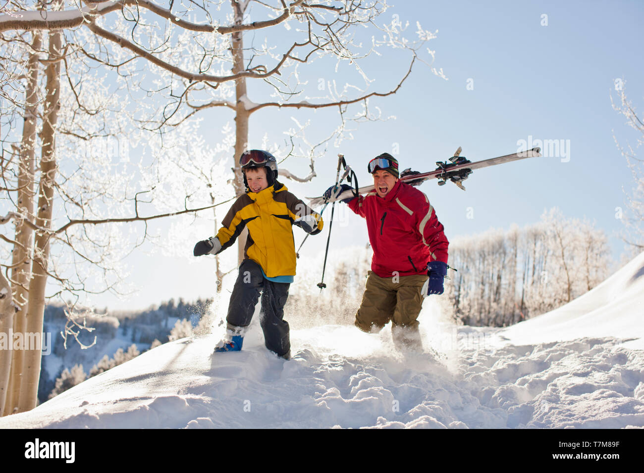 Happy father and young son running through snow carrying skis Stock ...