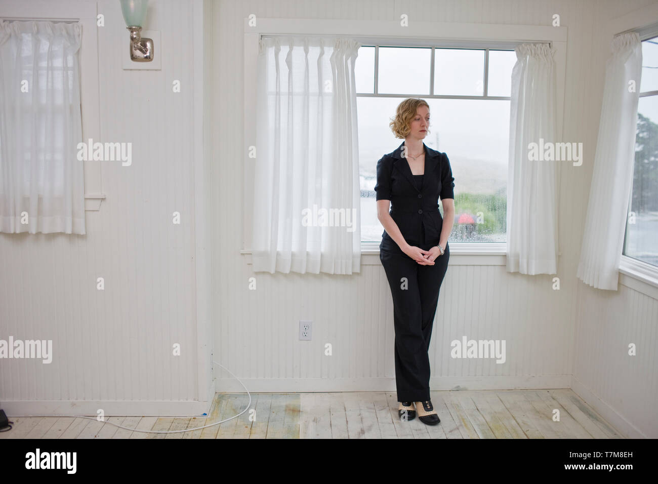Woman standing in house next to window Stock Photo - Alamy