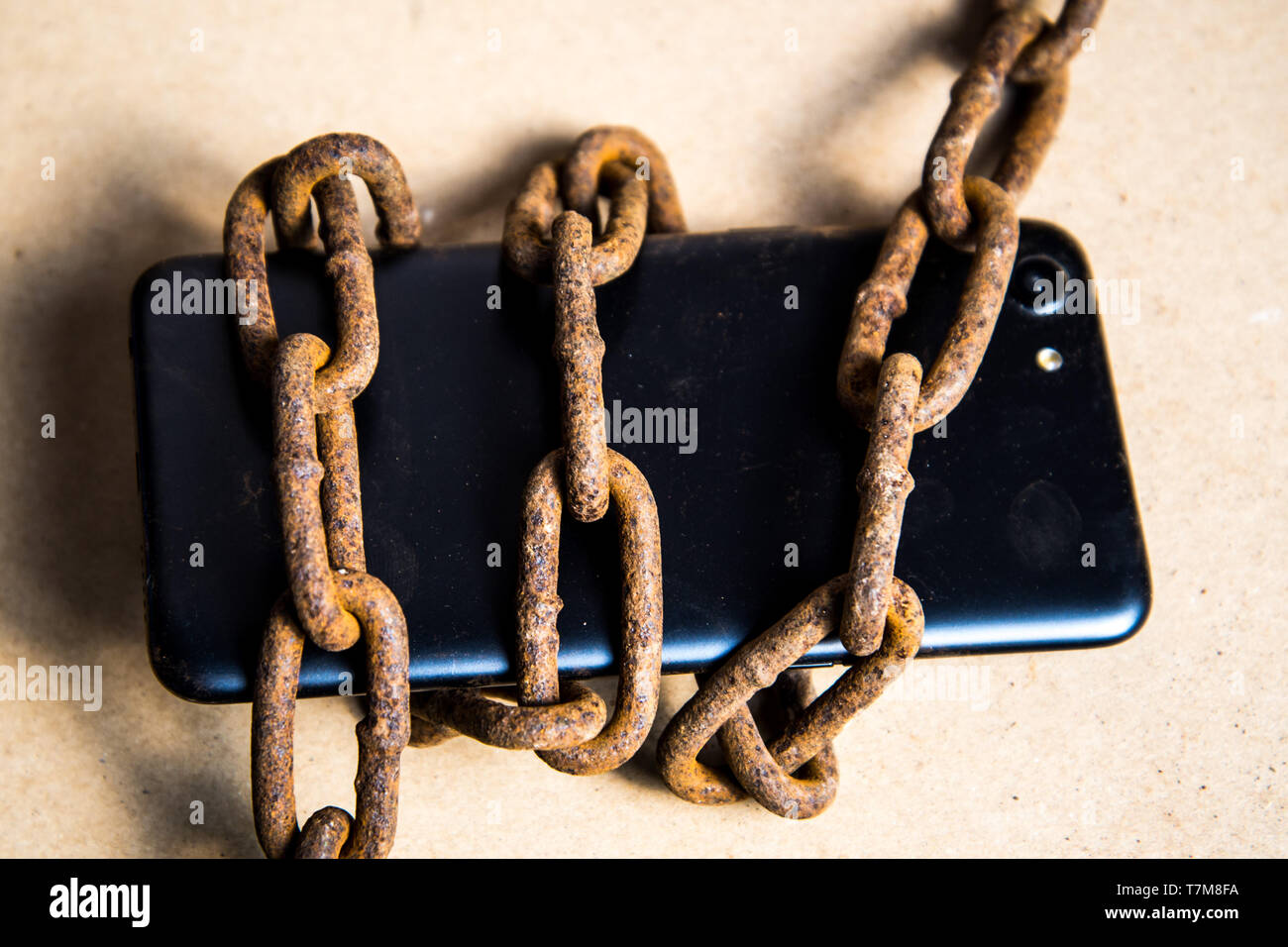 Smartphone in chains. Old rusty chains. Black smartphone Stock Photo ...