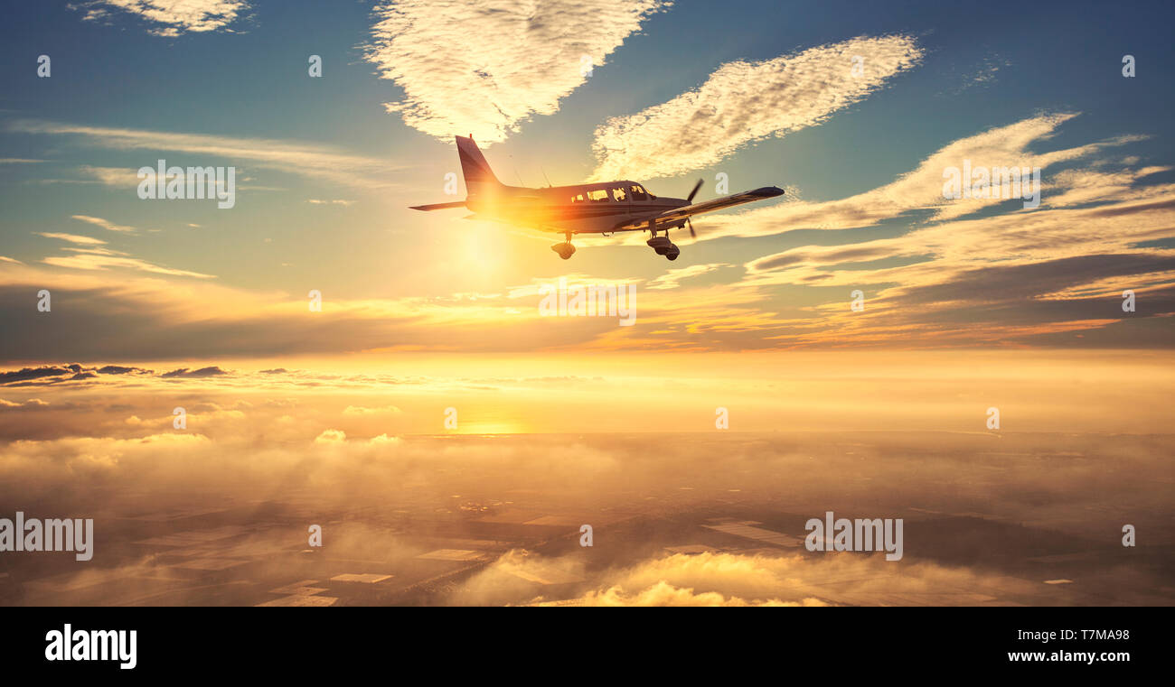 Small single engine airplane flying in the gorgeous sunset sky through ...