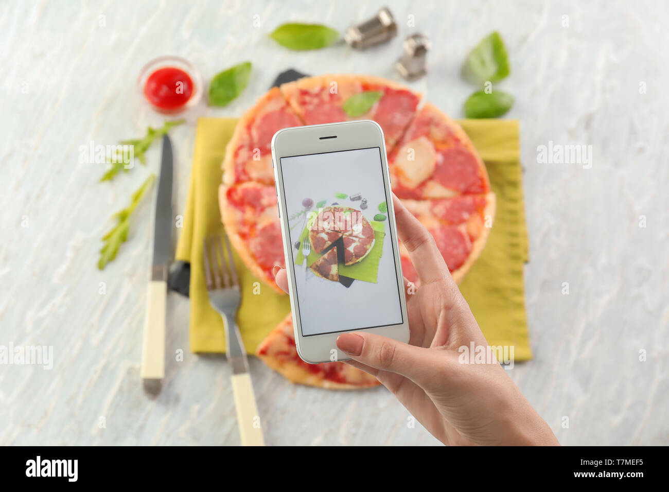 Woman photographing pepperoni pizza with mobile phone Stock Photo - Alamy