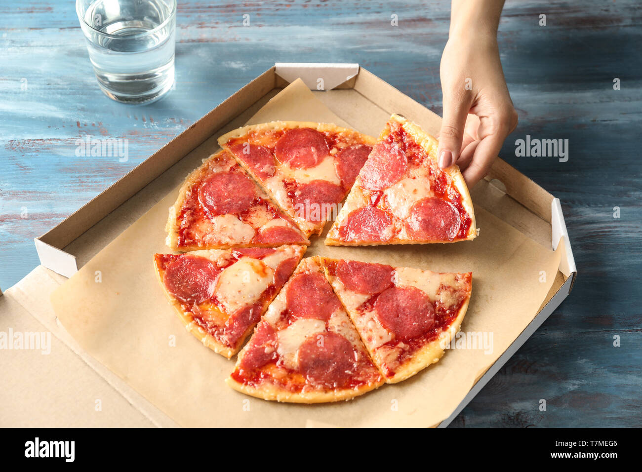 Woman eating pepperoni pizza at table Stock Photo - Alamy