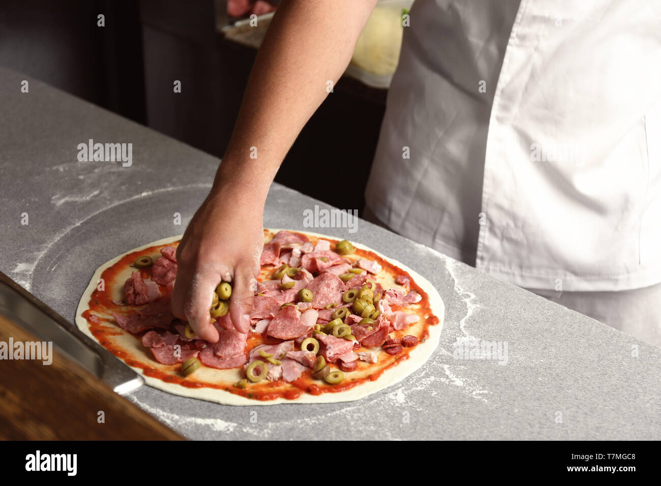 Chef preparing pizza on table in restaurant kitchen Stock Photo - Alamy