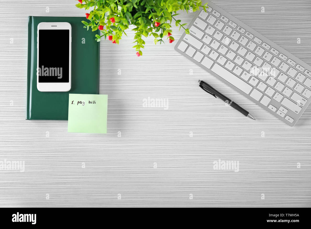 Sticker with phrase PAY BILL, computer keyboard and phone on light ...