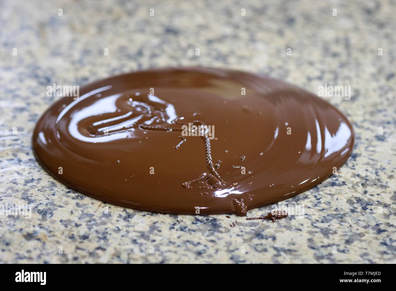 Liquid tempered chocolate poured on a granite table. Close-up Stock ...