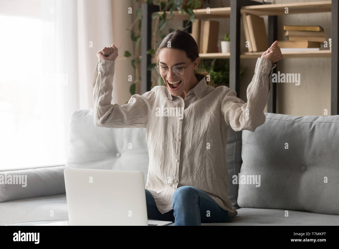 Excited woman looking at computer screen celebrating online win Stock ...