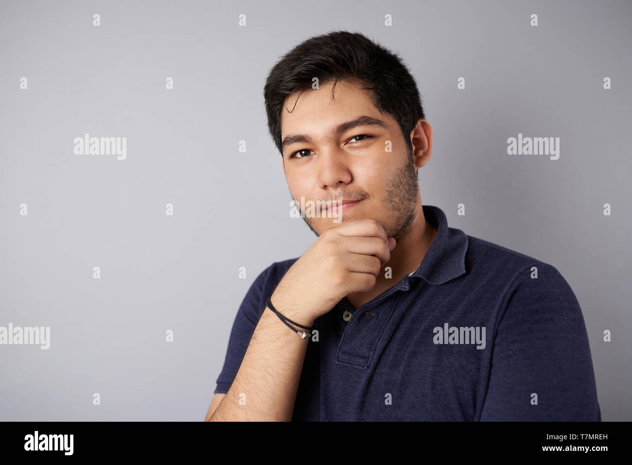 Latin young man thinking pose in studio gray background Stock Photo - Alamy