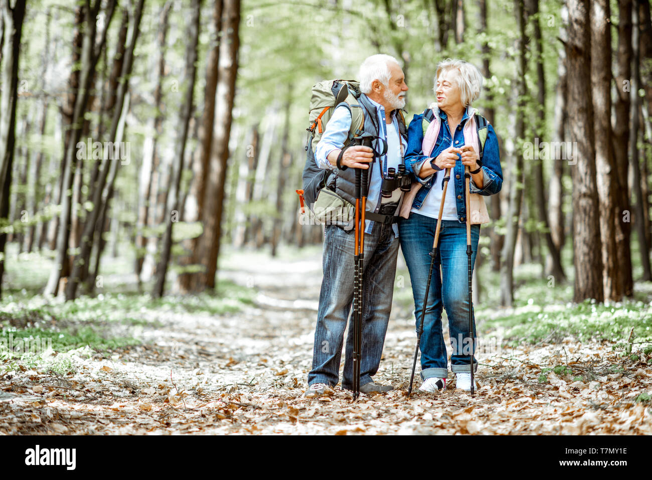 Beautiful senior couple hiking with backpacks and trekking sticks in ...