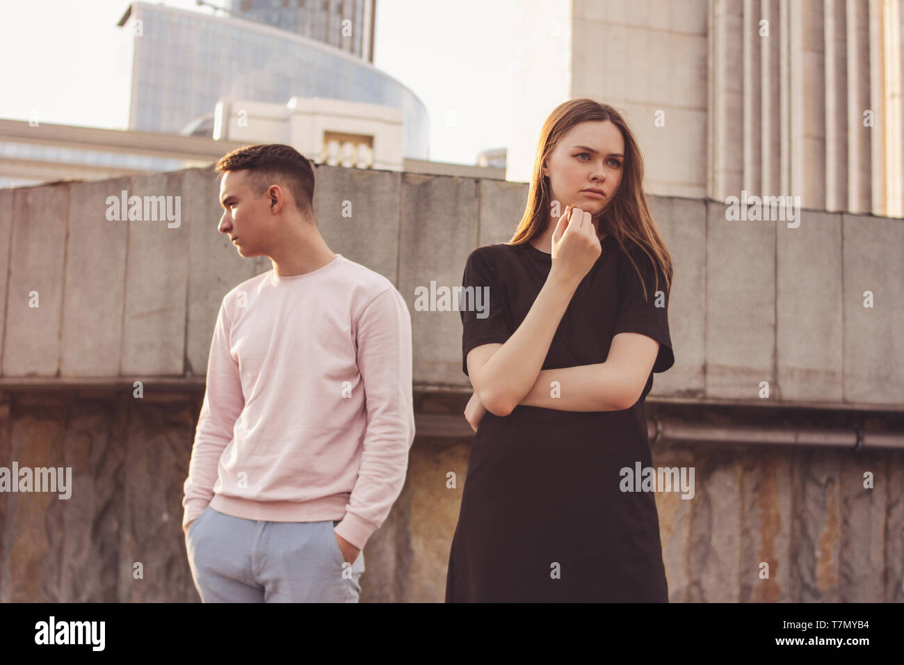 Unhappy young couple of friends, teenagers, students at city street ...