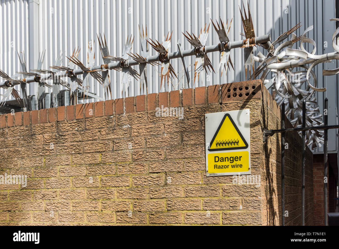 Razor wire on a brick wall with a danger sign underneath, UK Stock ...