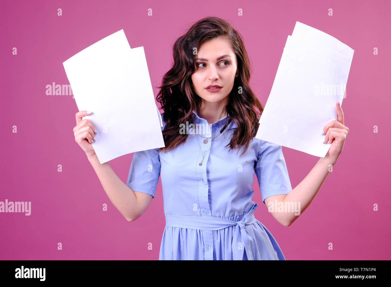 Young caucasian brunette woman holding paper over pink background ...