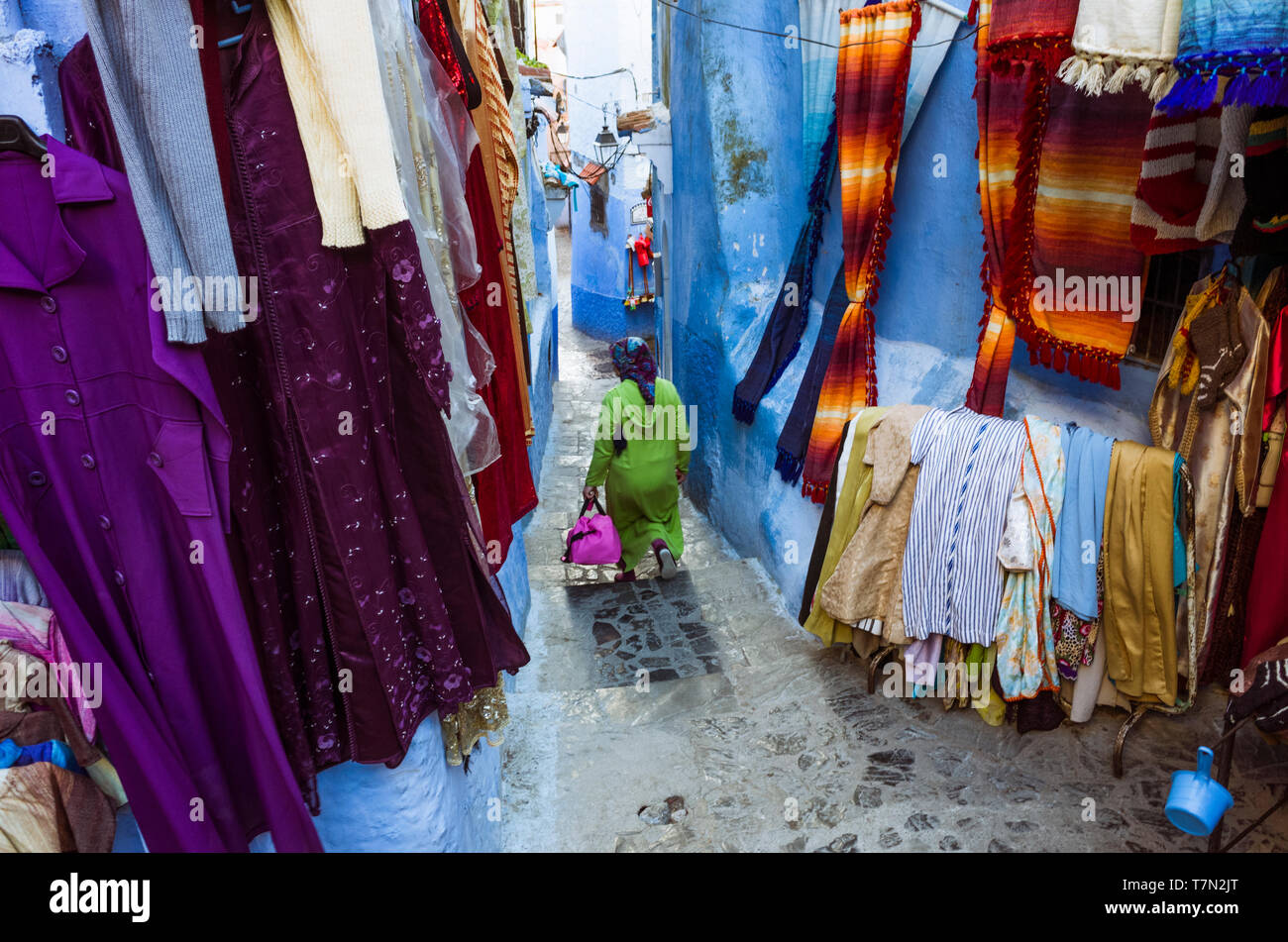 Chefchaouen, Morocco : A woman walks past a clothing store in the blue ...
