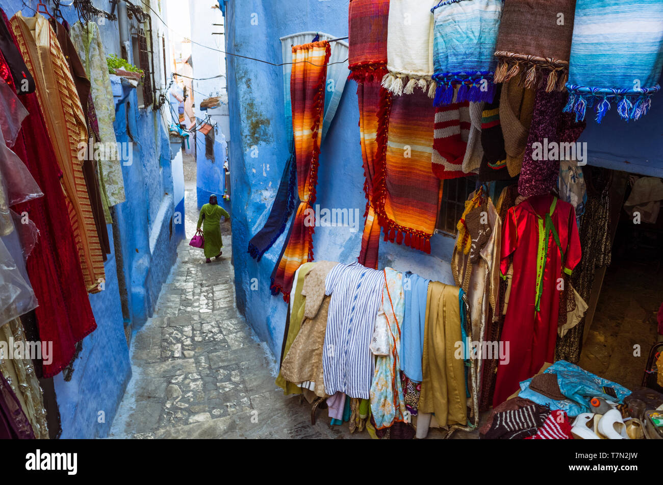 Chefchaouen, Morocco : A woman walks past a clothing store in the blue ...