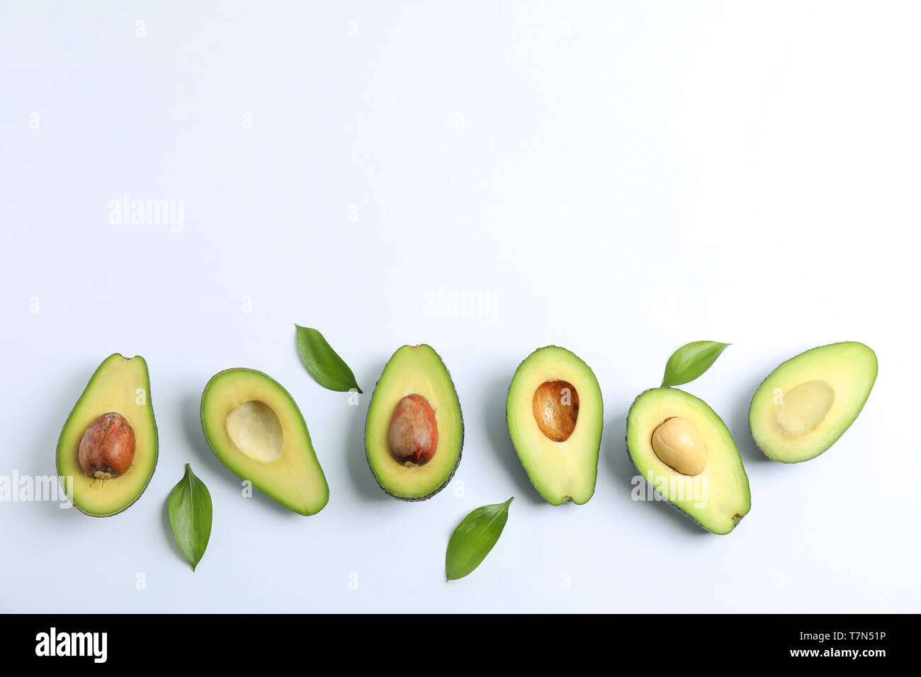 Flat lay composition with ripe avocados on white background, space for ...