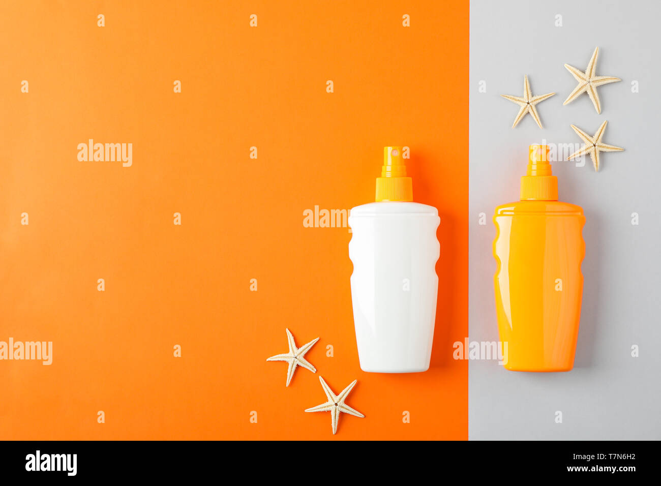 Flat lay composition with sunscreen sprays and starfishes on two tone ...