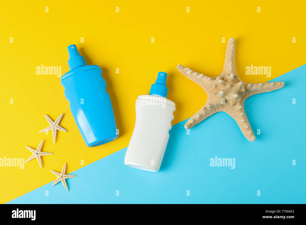 Flat lay composition with sunscreen sprays and starfishes on two tone ...