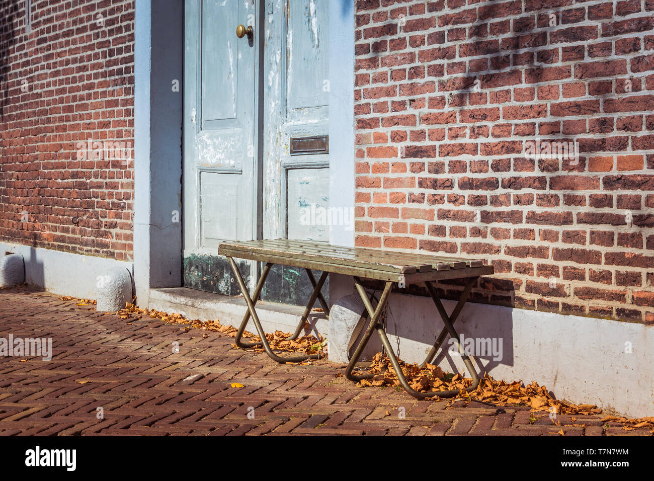 Outdoor bench in front of brick wall near door Stock Photo - Alamy